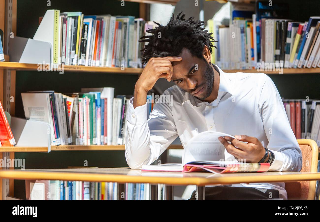 Teenage Students, reading library. A young adult man reading through ...