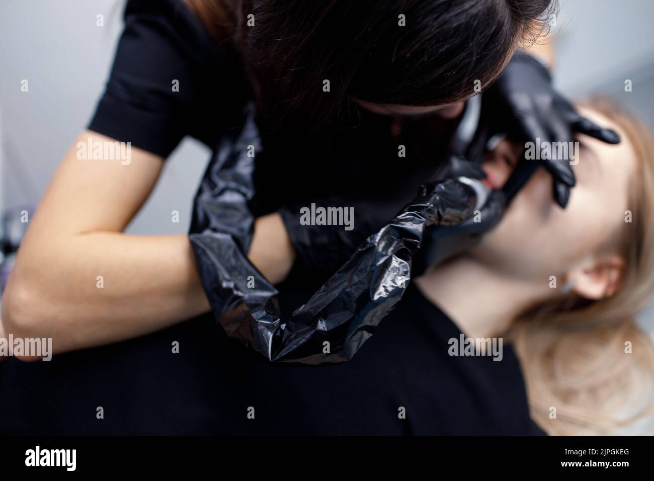 Cosmetologist master apply red permanent lips tattoo for girl Stock ...