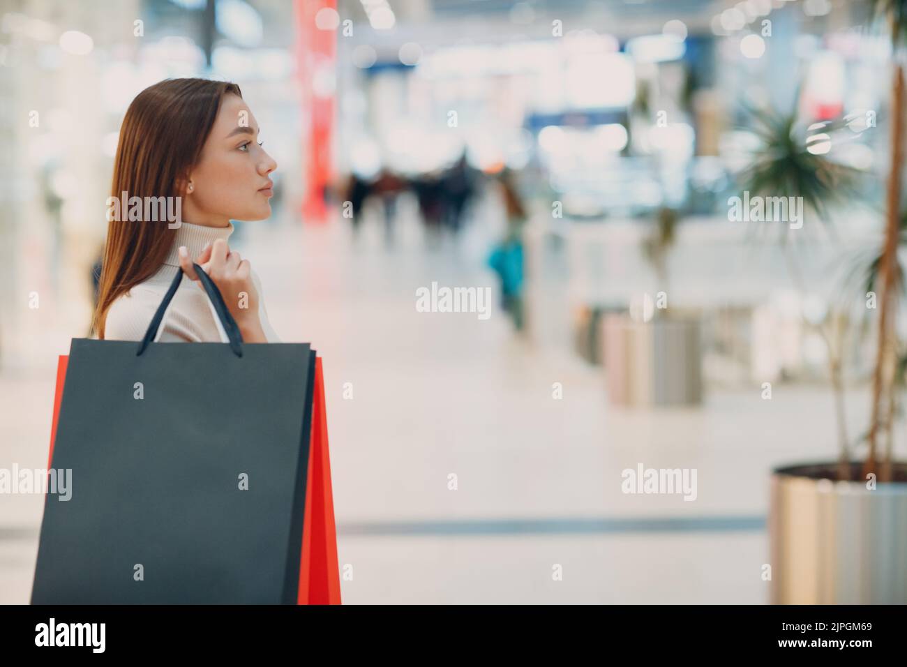 Positive young adult woman carrying paper shopping bags Stock Photo - Alamy