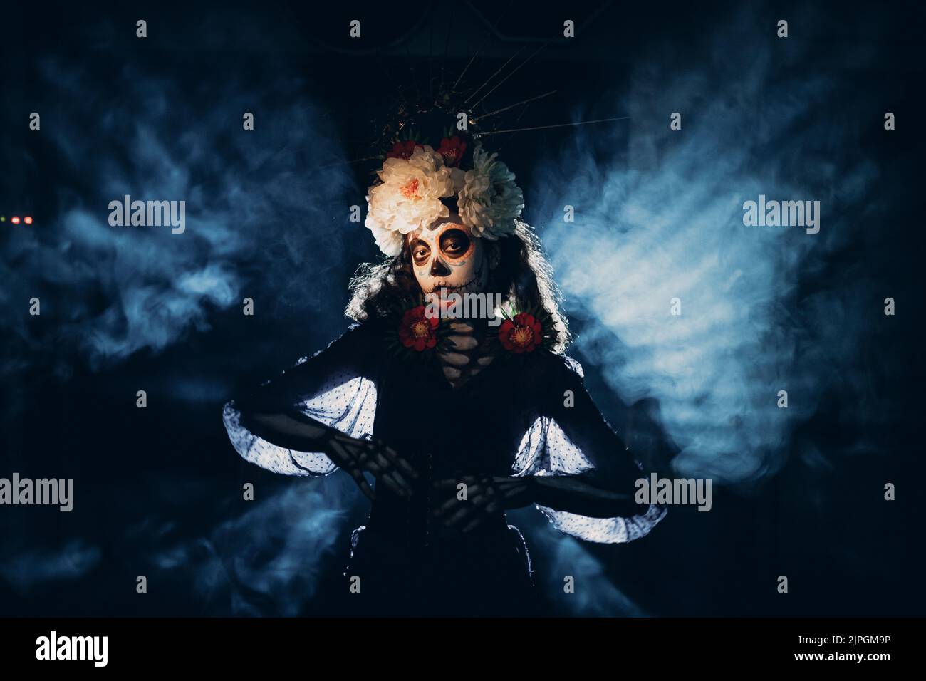 Woman with mexican skull halloween makeup in dark with backlight rays ...