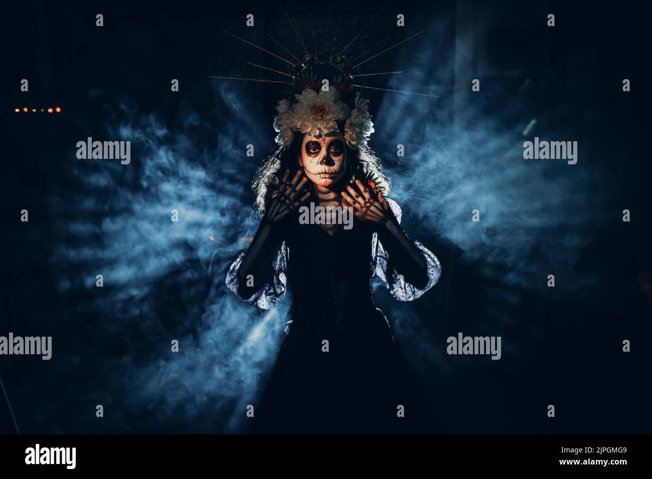 Woman with mexican skull halloween makeup in dark with backlight rays ...