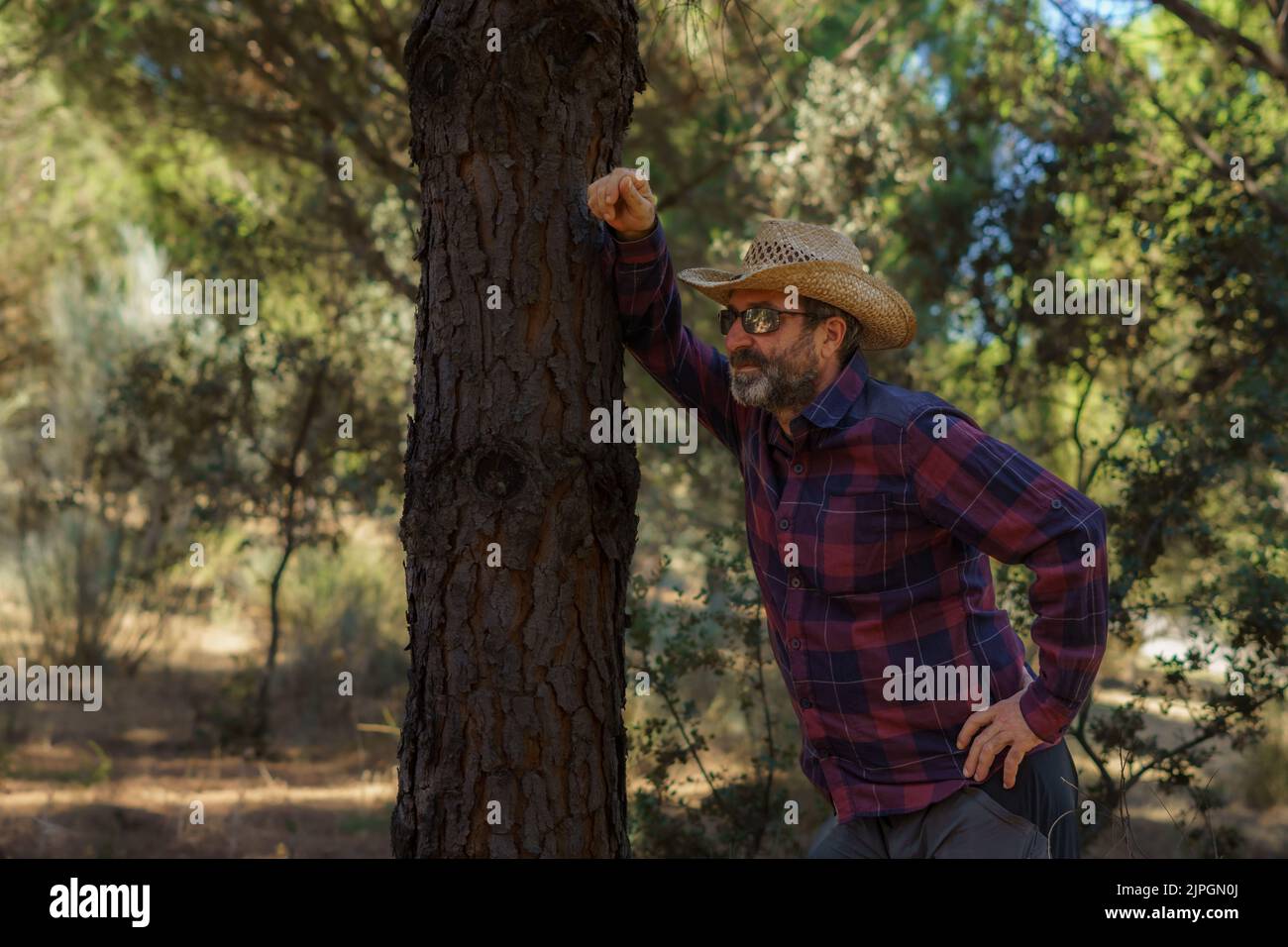 close-up of a man with a beard, hat and sunglasses leaning against a ...