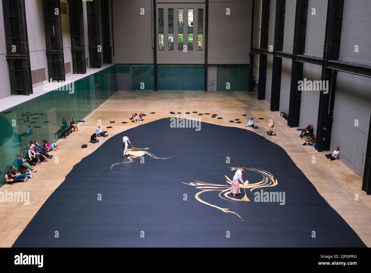 Performers in traditional dress push rice with brooms in a work titled ...