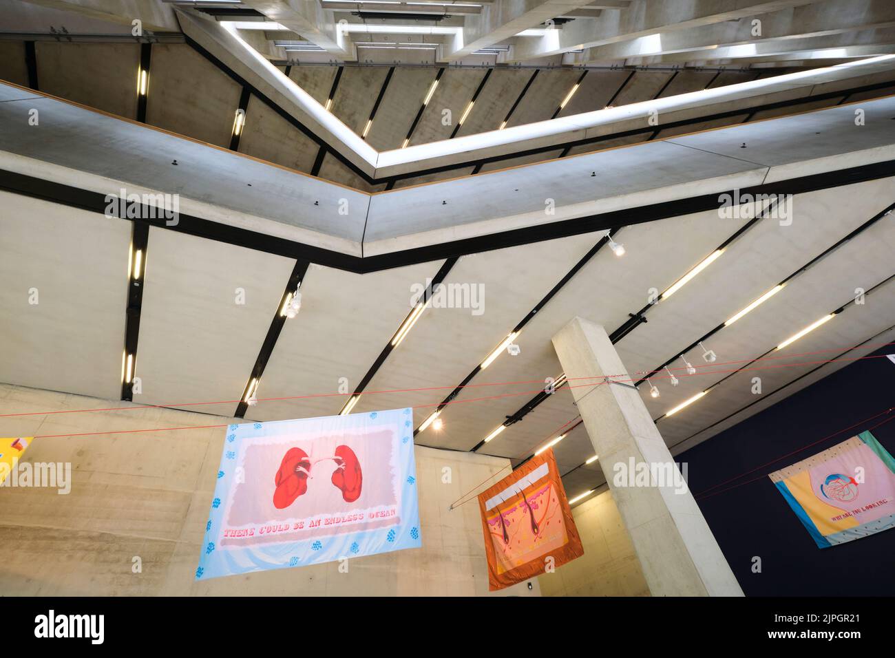 Textiles hanging in the soaring atrium of raw, unfinished concrete. In ...