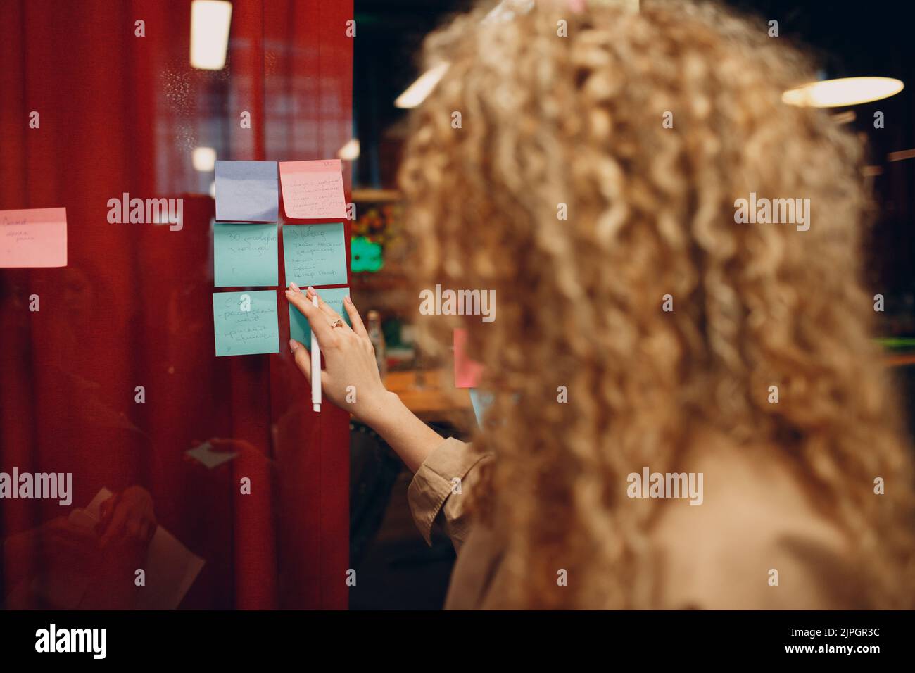 Business people woman writing on sticky note on glass wall with ...