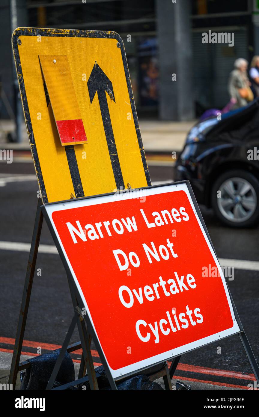 Narrow Lanes Do Not Overtake Cyclists sign below a lane closure traffic ...