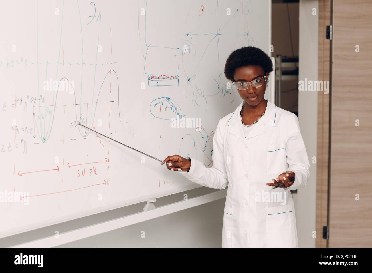 African American woman math teacher stands at blackboard with pointer ...