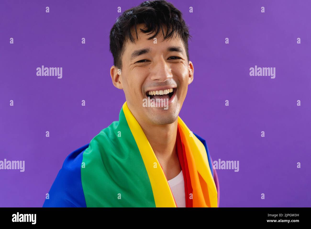 Portrait of happy biracial man holding lgbt rainbow flag and smiling on ...