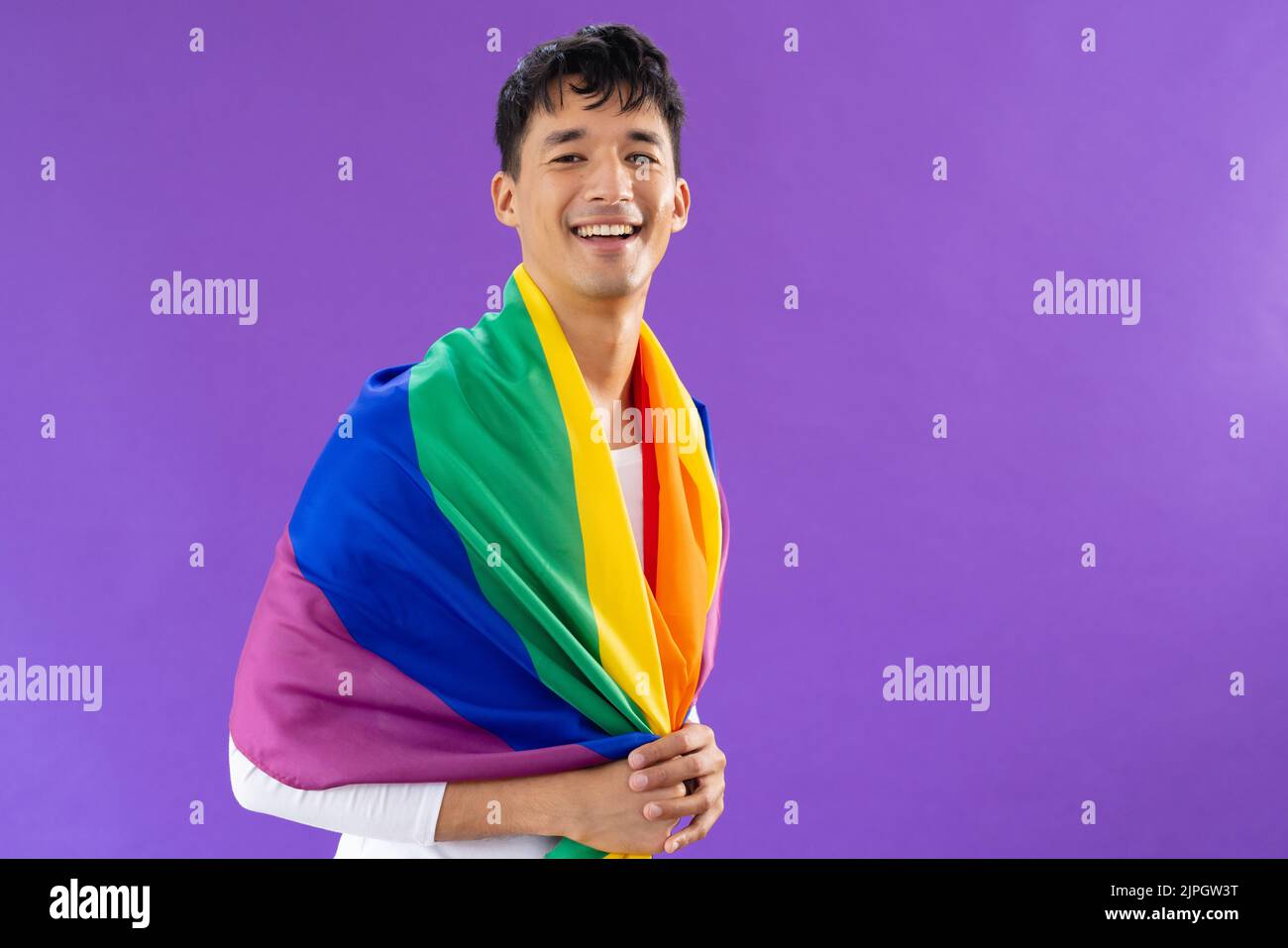 Portrait of happy biracial man holding lgbt rainbow flag and smiling on ...