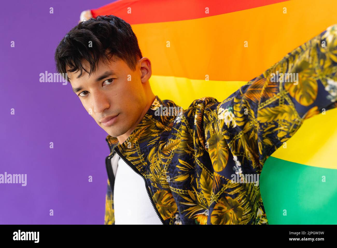 Portrait of happy biracial man holding lgbt rainbow flag and smiling on ...