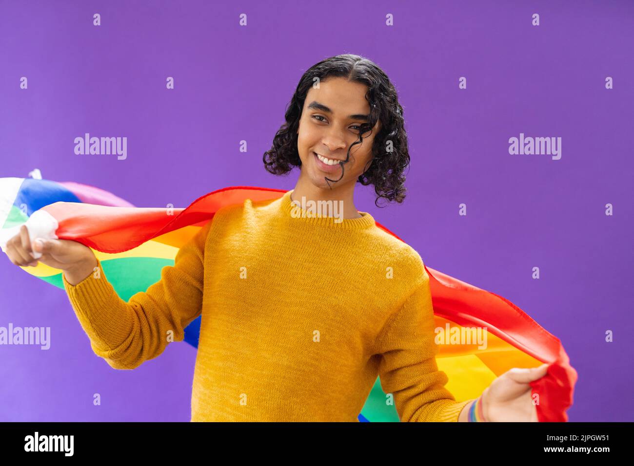 Portrait of happy biracial man holding lgbt rainbow flag and smiling on ...