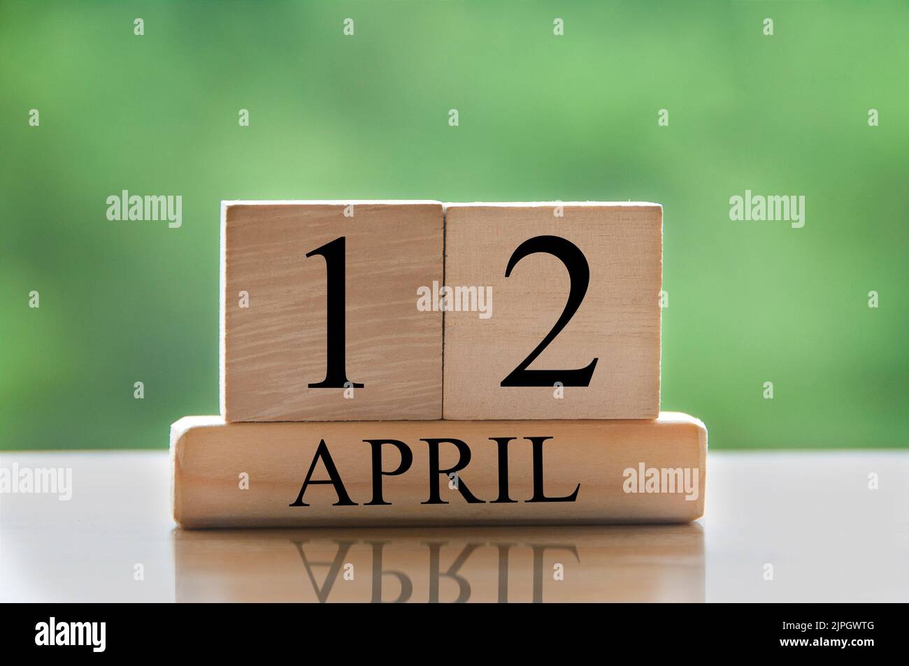 April 12 calendar date text on wooden blocks with blurred park ...