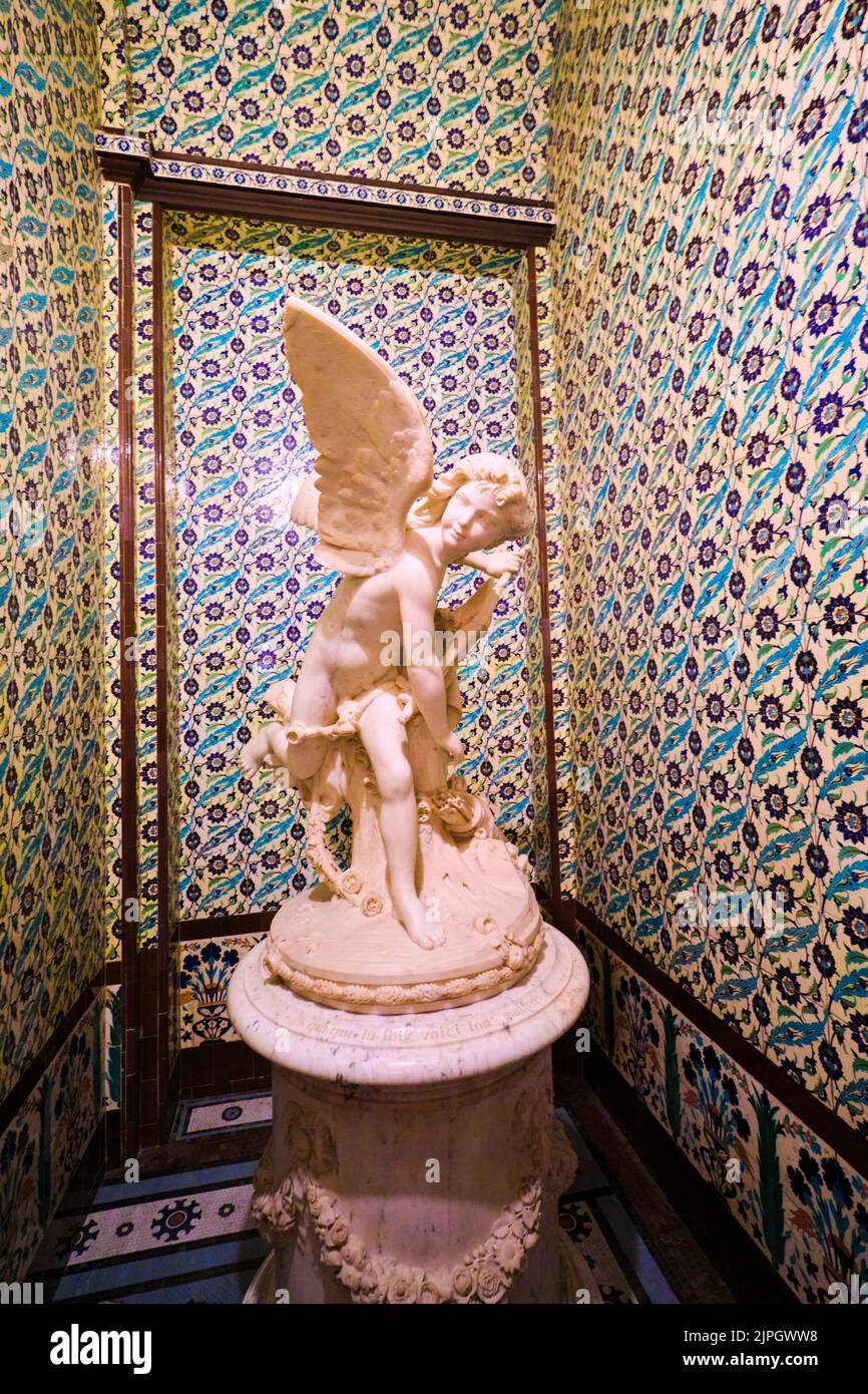 A white marble carved angel, in an alcove covered in fancy tilework. At ...