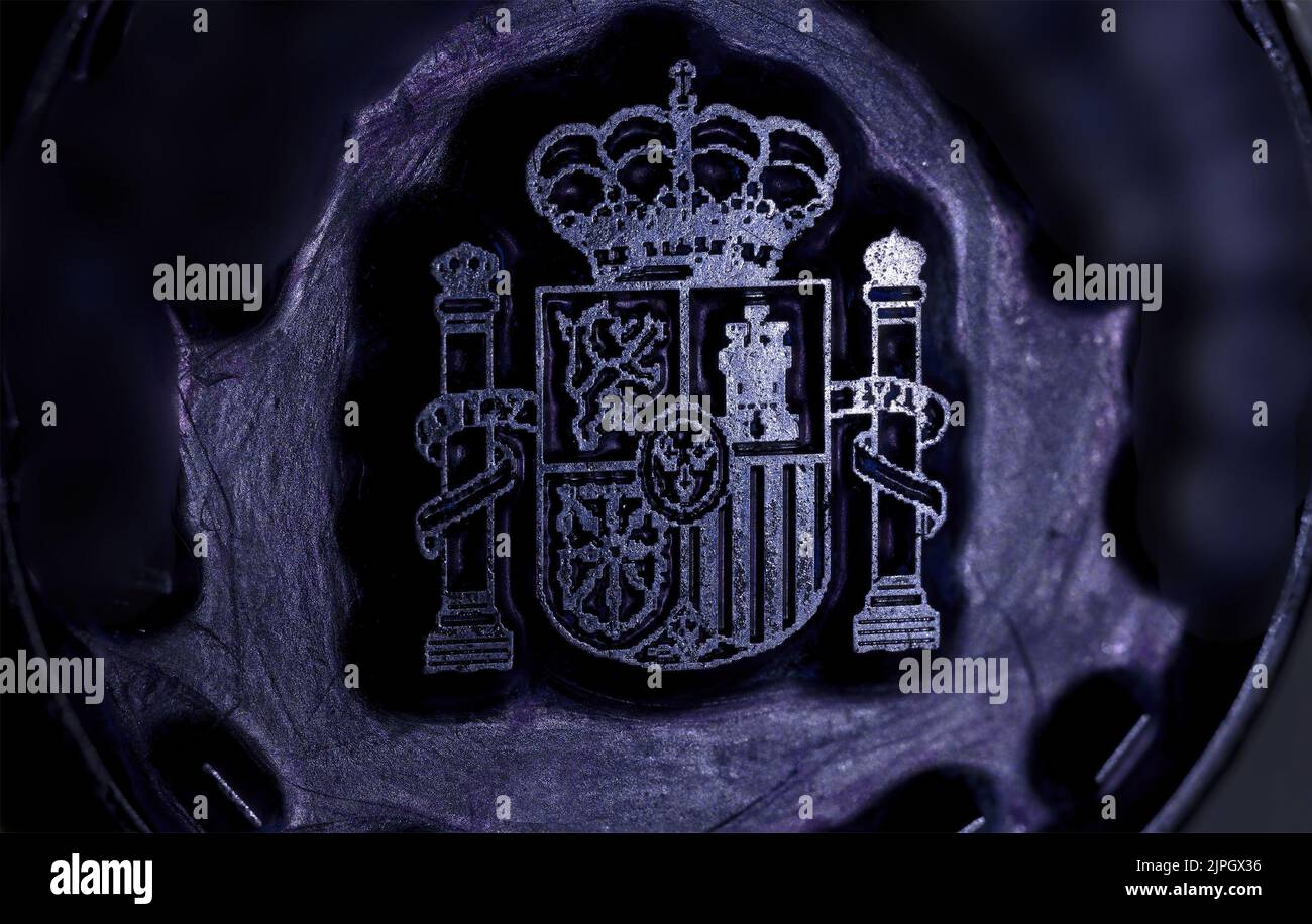 Coat of arms of Spain engraved in a stamp, dark photo with side light ...
