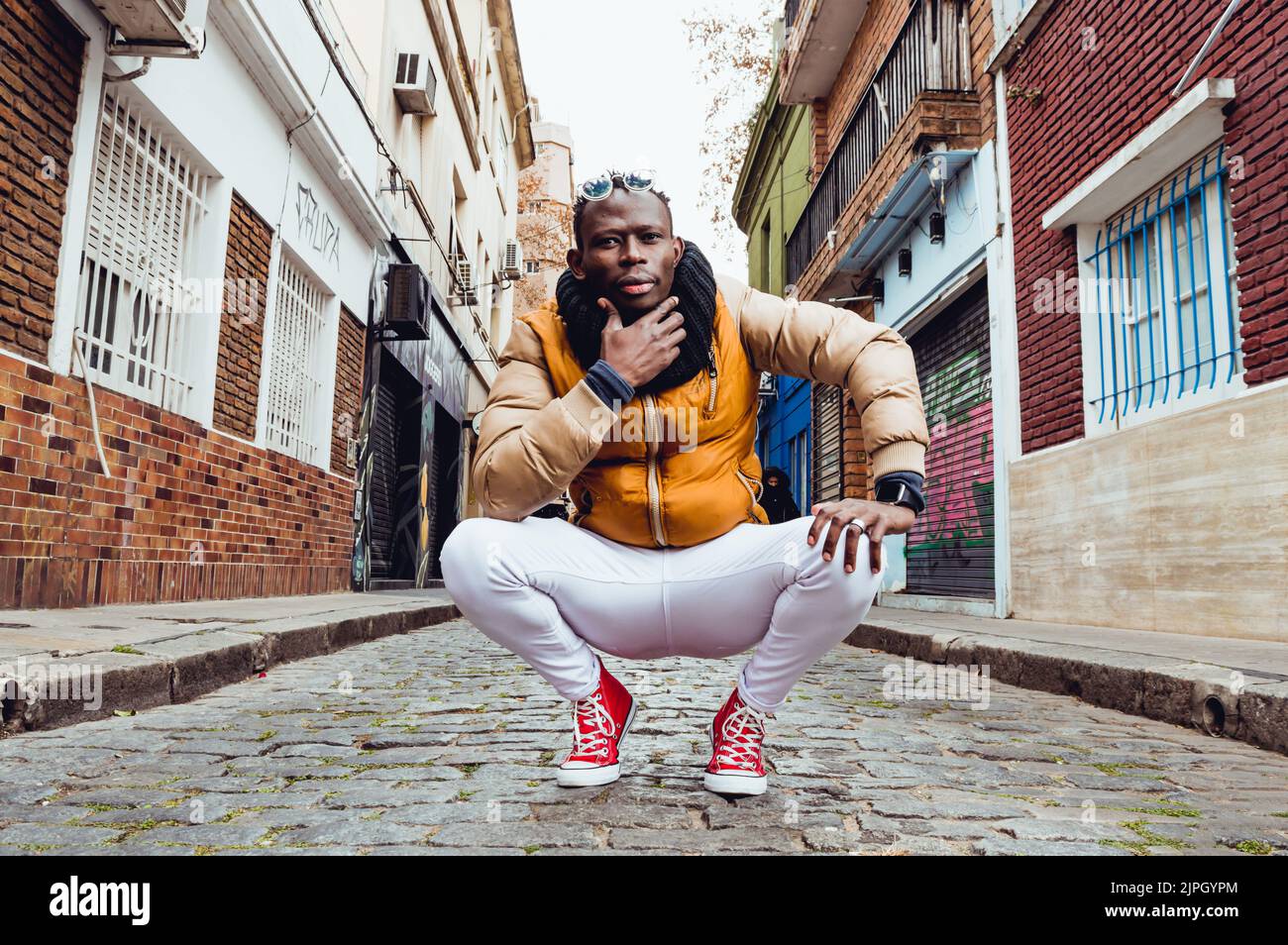 young man of african ethnicity crouching in the street looking at the ...