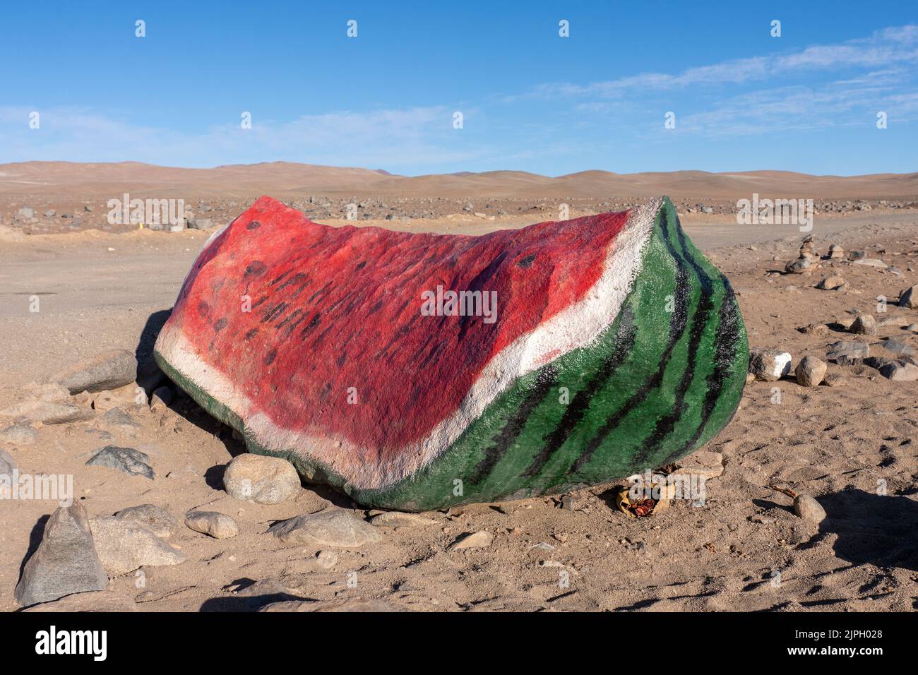 A large rock painted as a watermelon alongside a road across the ...