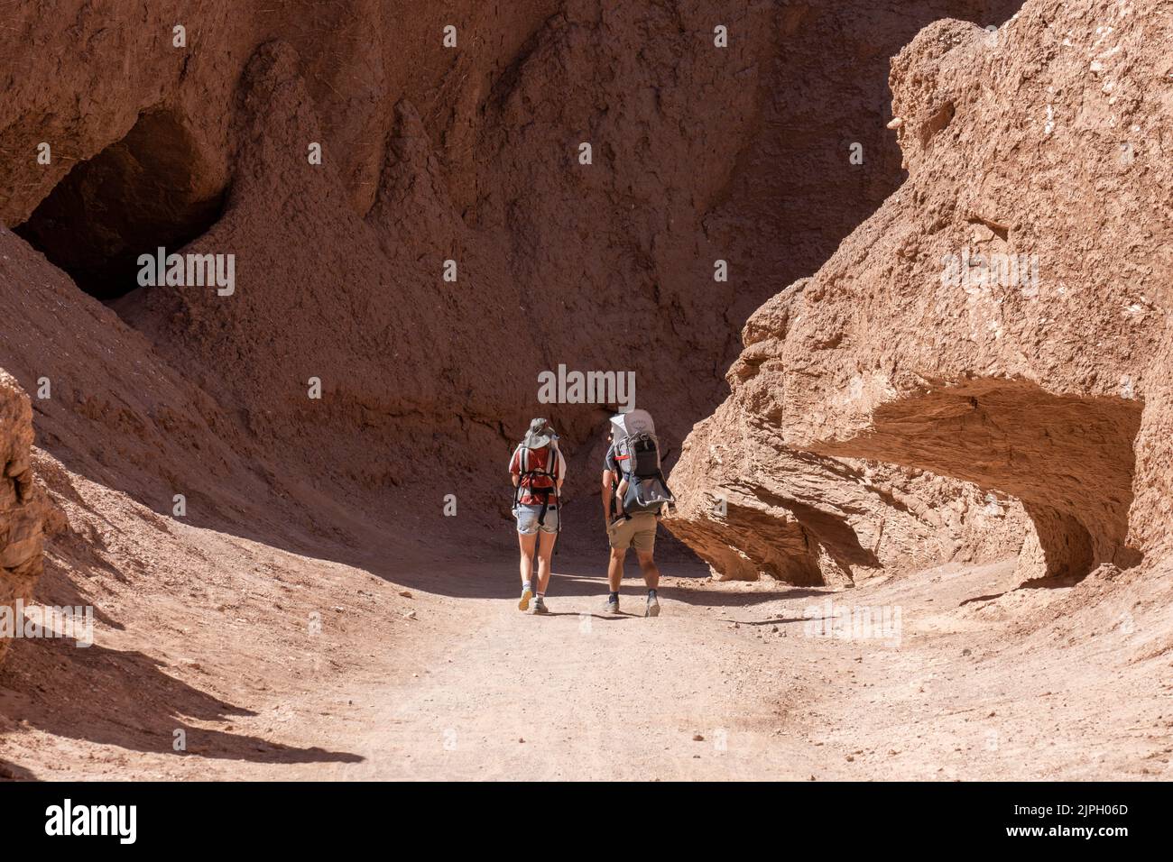 A couple of tourists hiking in the Devil's Throat Canyon, carrying ...