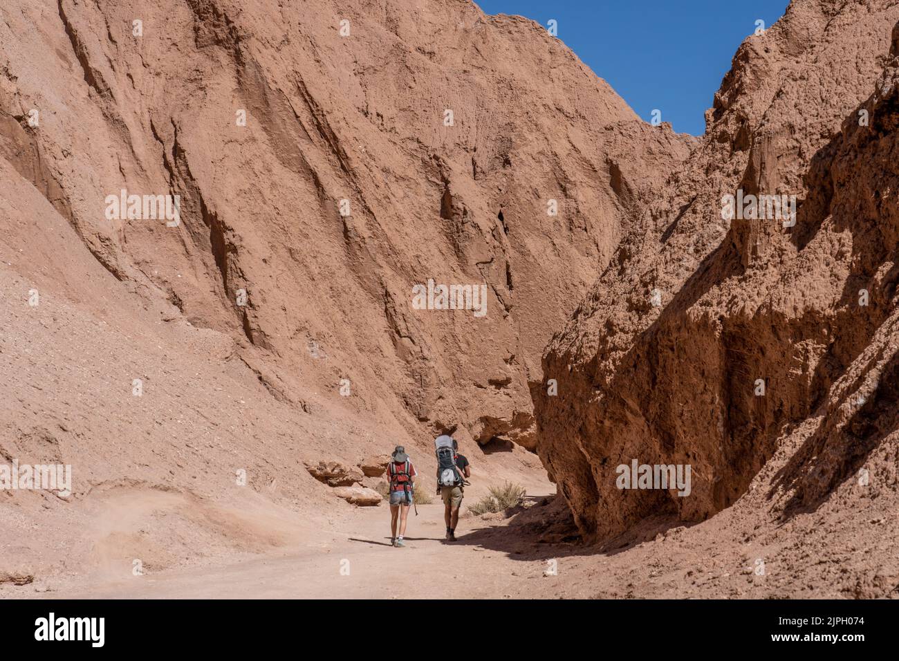 A couple of tourists hiking in the Devil's Throat Canyon, carrying ...
