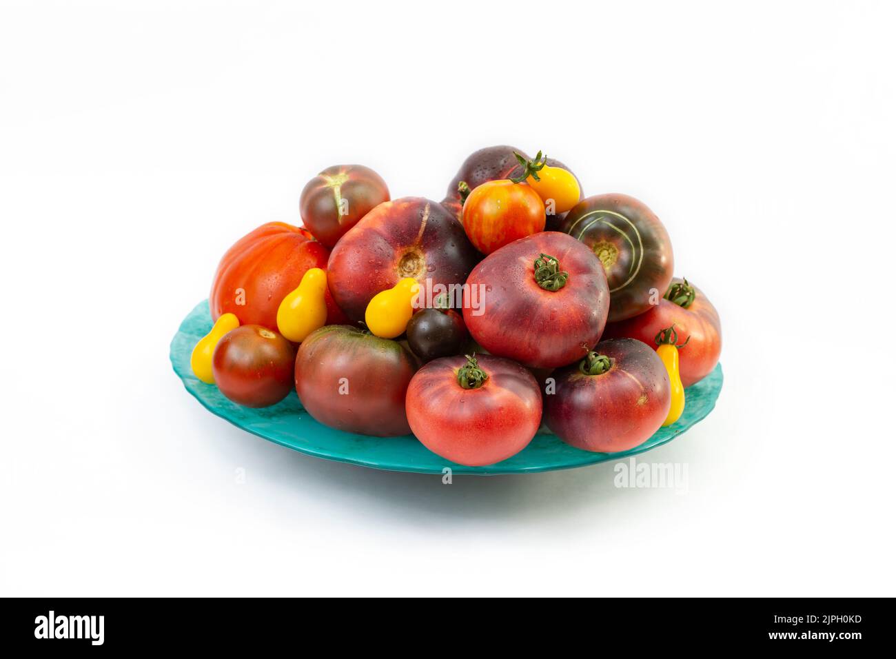 Various tomato colors piled up on a green plate, isolated on white ...