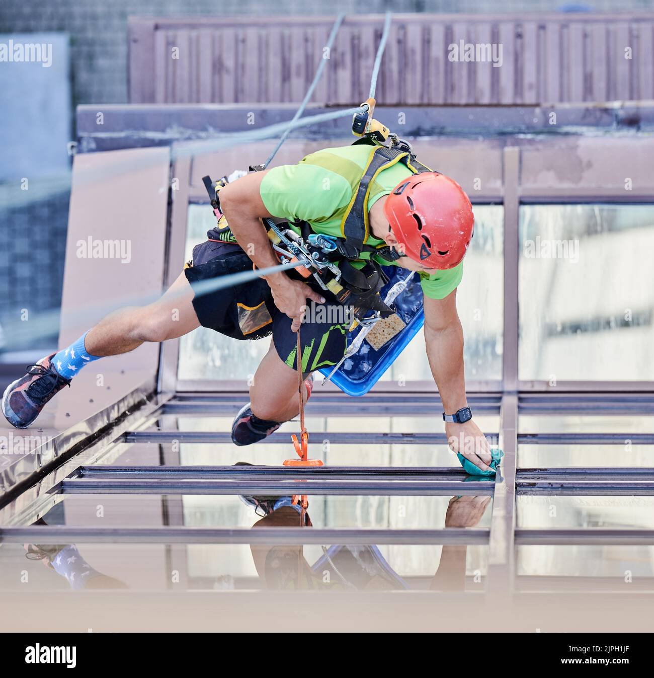 Industrial mountaineering worker washing glass windows of high-rise ...