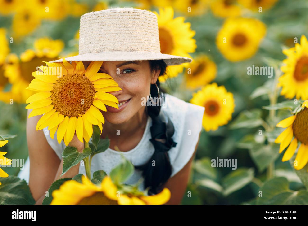 Beautiful smiling young woman in a hat with flower on her eye and face ...