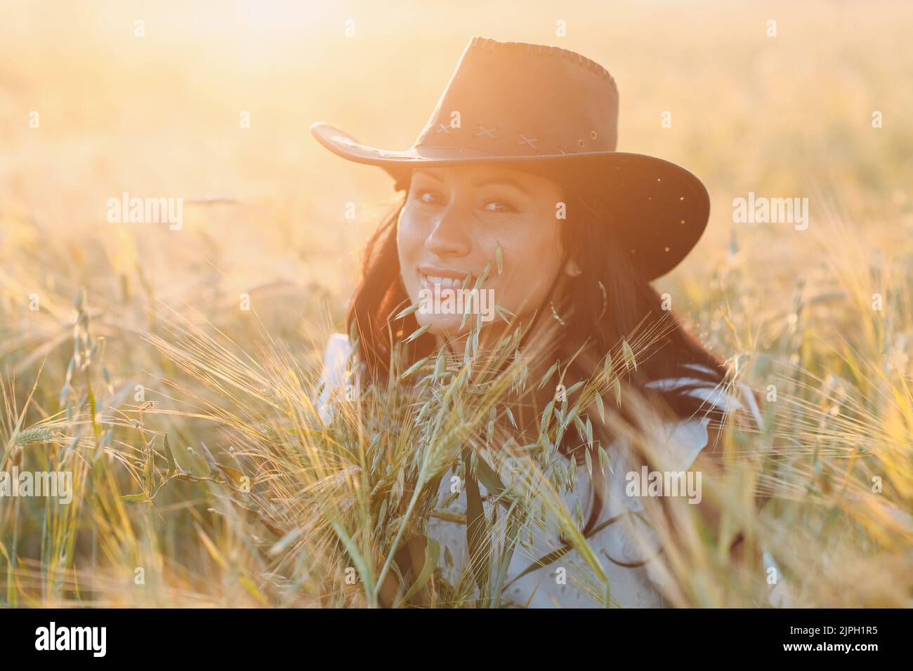 Woman farmer in cowboy hat at agricultural field on sunset Stock Photo ...