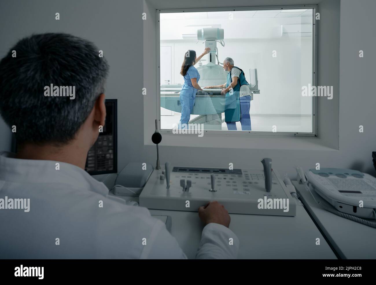 Female nurse preparing mature patient for X-ray of hand near X-ray ...