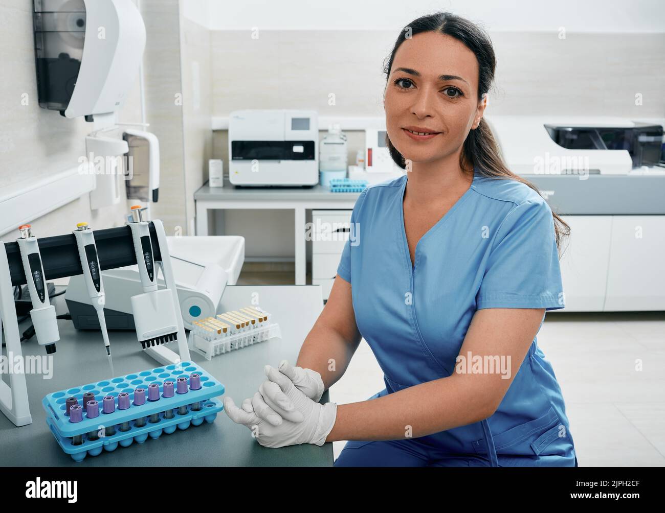 Portrait of positive female lab technician against medical modern ...