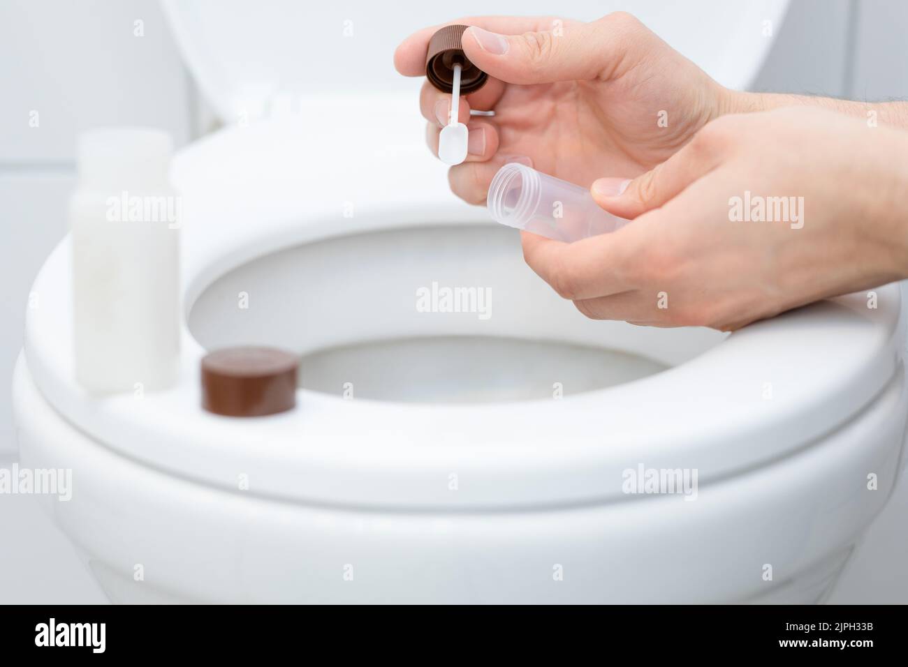 The male hands on toilet with plastic bottle in hand collecting stool ...