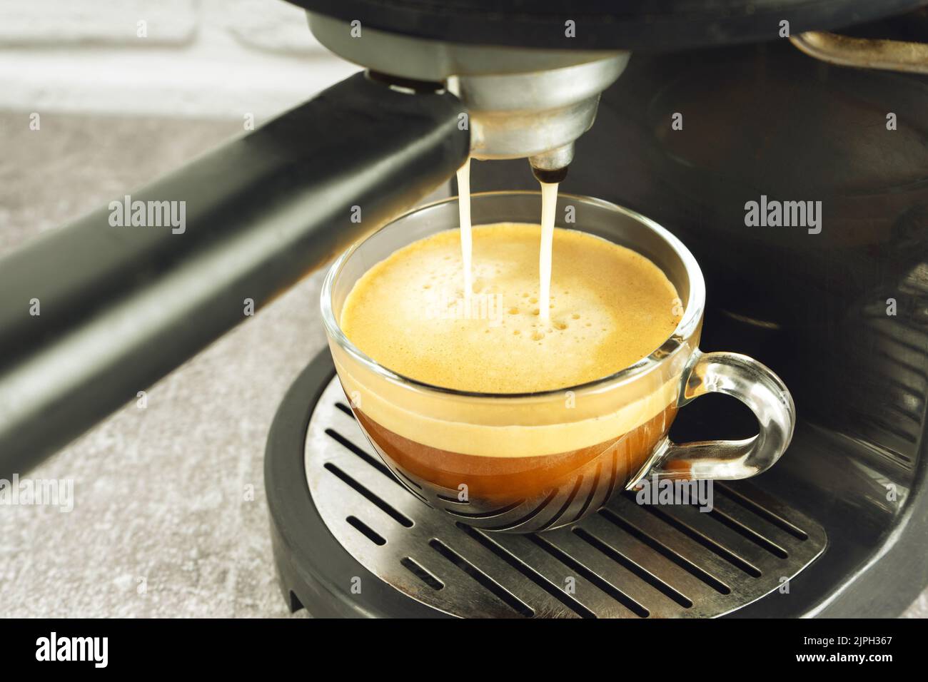 Glass cup standing on the grating of black coffee machine and coffee ...