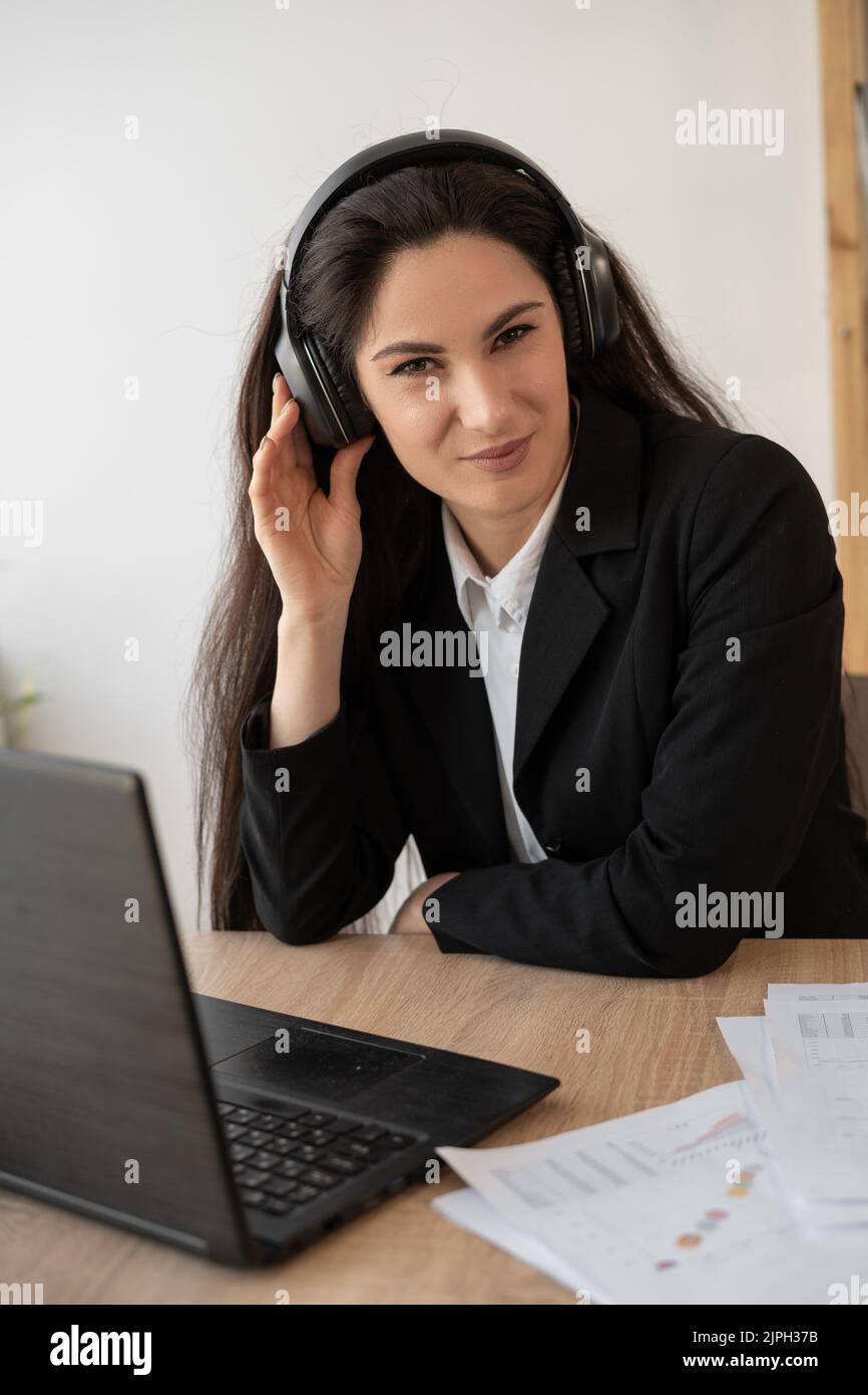 Portrait of a happy woman working on a laptop while talking with a ...