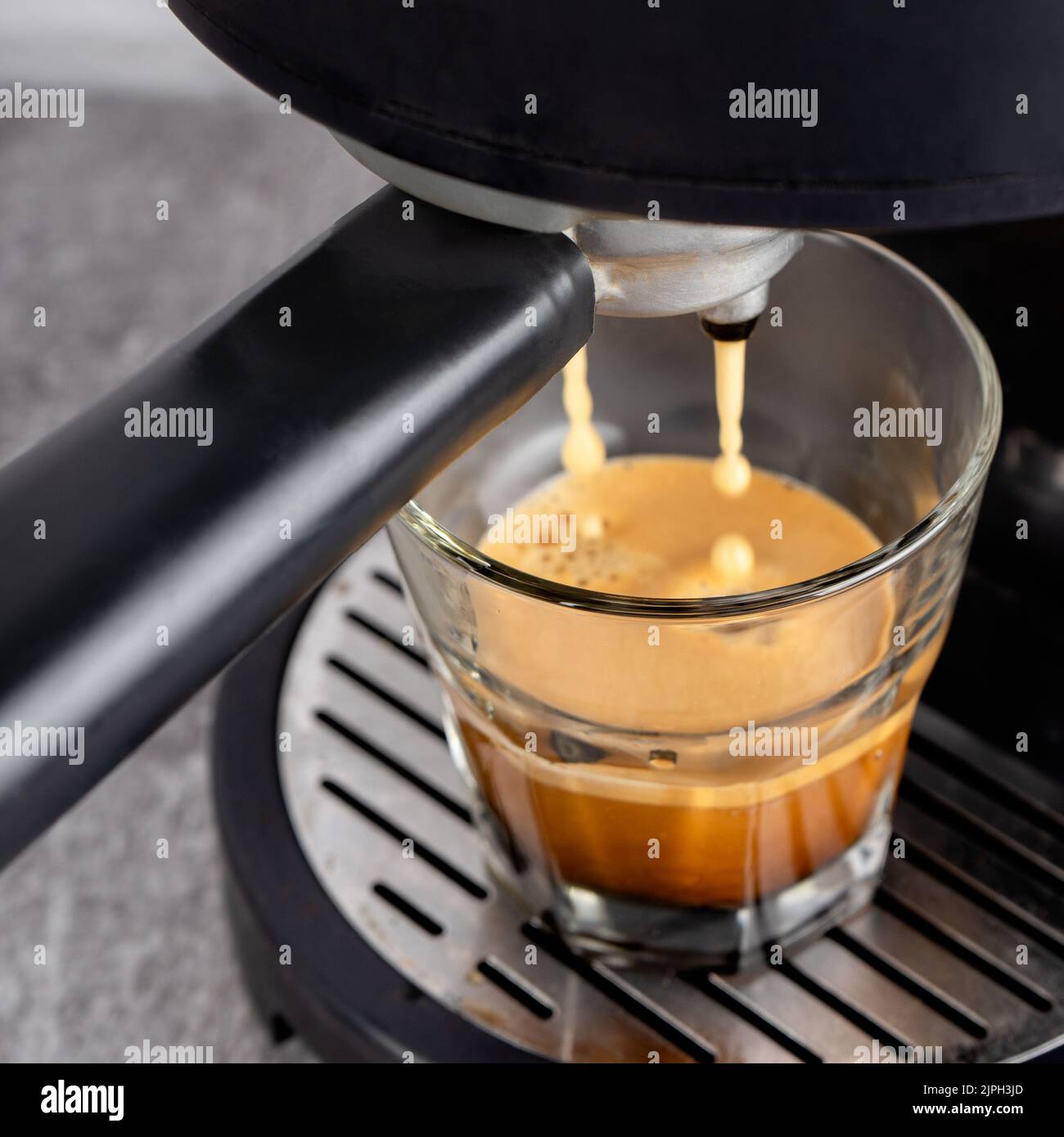 Glass cup standing on the grating of black coffee machine and coffee ...