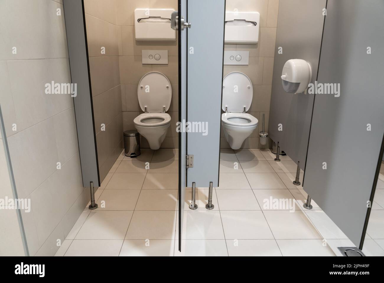 Row of clean toilet cubicles with open door in a public restroom Stock ...