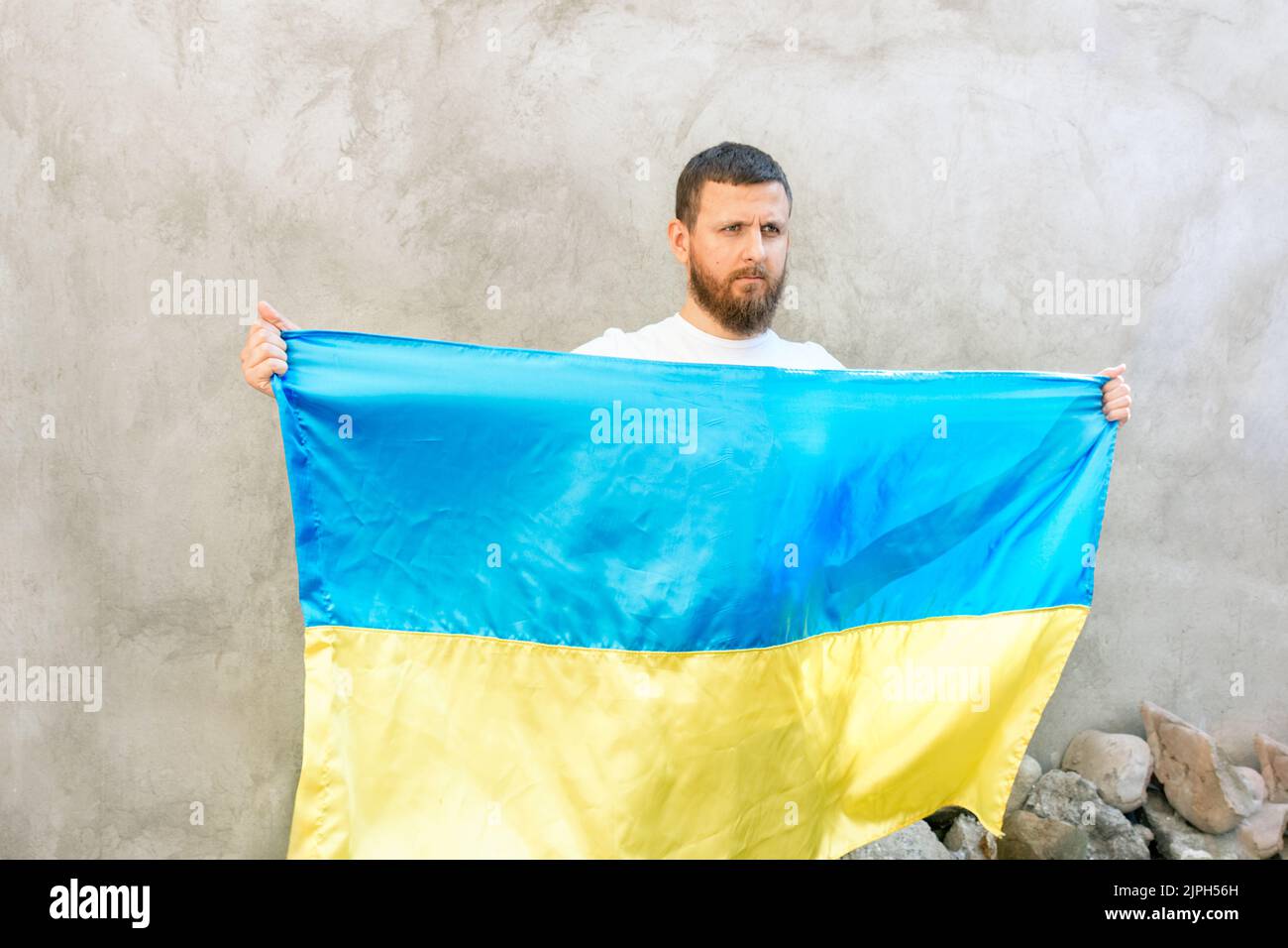 Man holds the national blue-yellow flag of Ukraine in front of him. A ...
