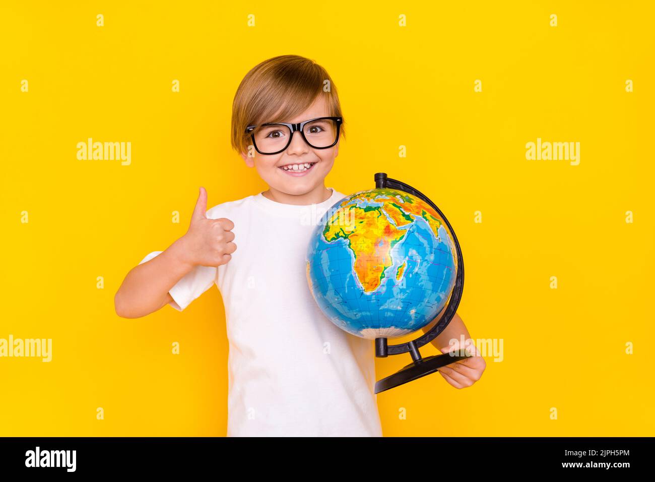 Portrait of handsome cheerful genius pre-teen boy holding globe showing ...