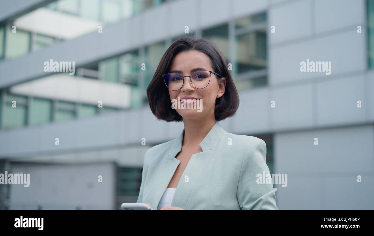 Busy lady looking at the camera while tapping or scrolling on ...