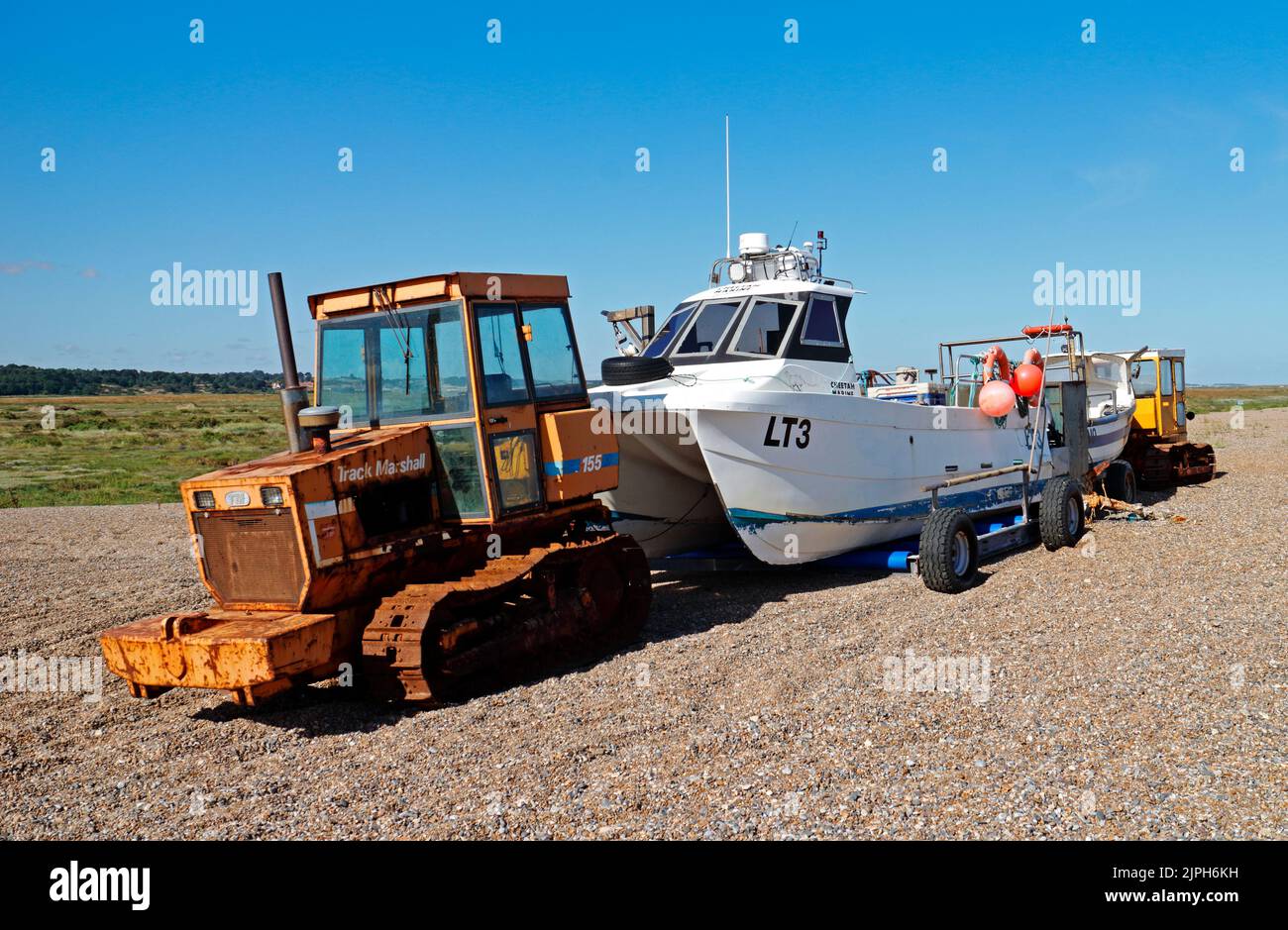 Inshore fishing boats and trailers with tractors beached above high ...