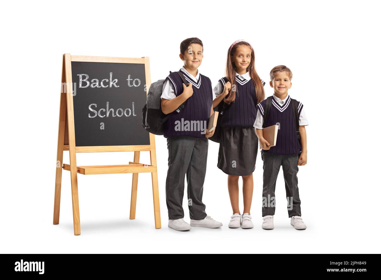Schoolchildren with backpacks standing next to a blackboard on a stand ...