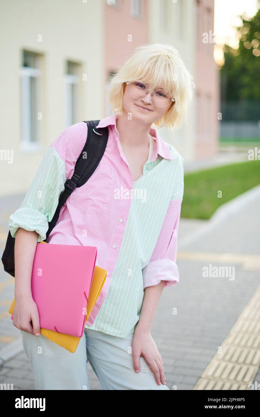 smiling student girl holding pink folder with books and carry school ...
