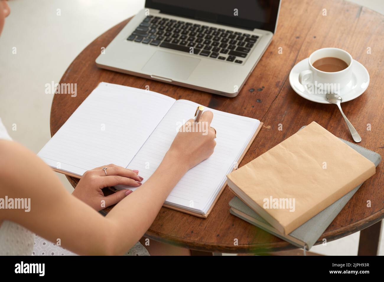 Female student writing notes in her textbook when sitting in cafe Stock ...