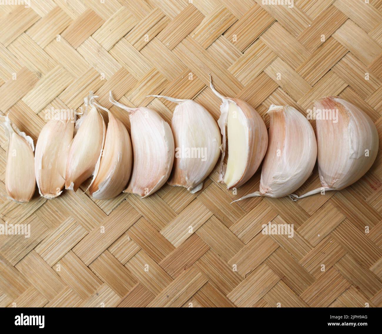 unpeeled garlic on a woven bamboo background Stock Photo - Alamy