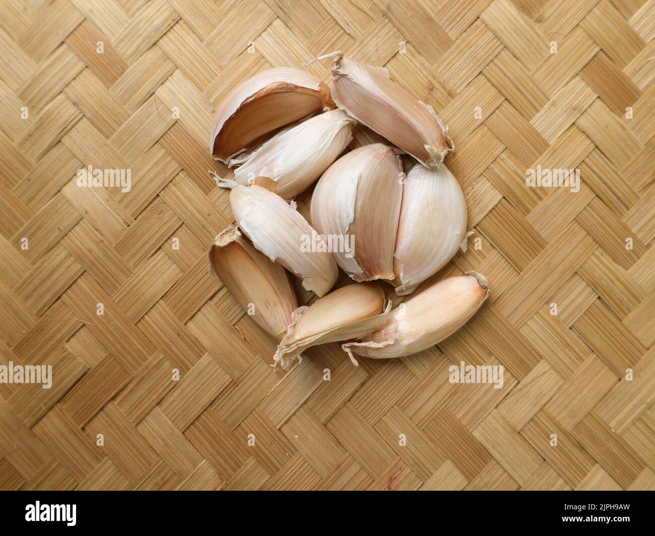 unpeeled garlic on a woven bamboo background Stock Photo - Alamy