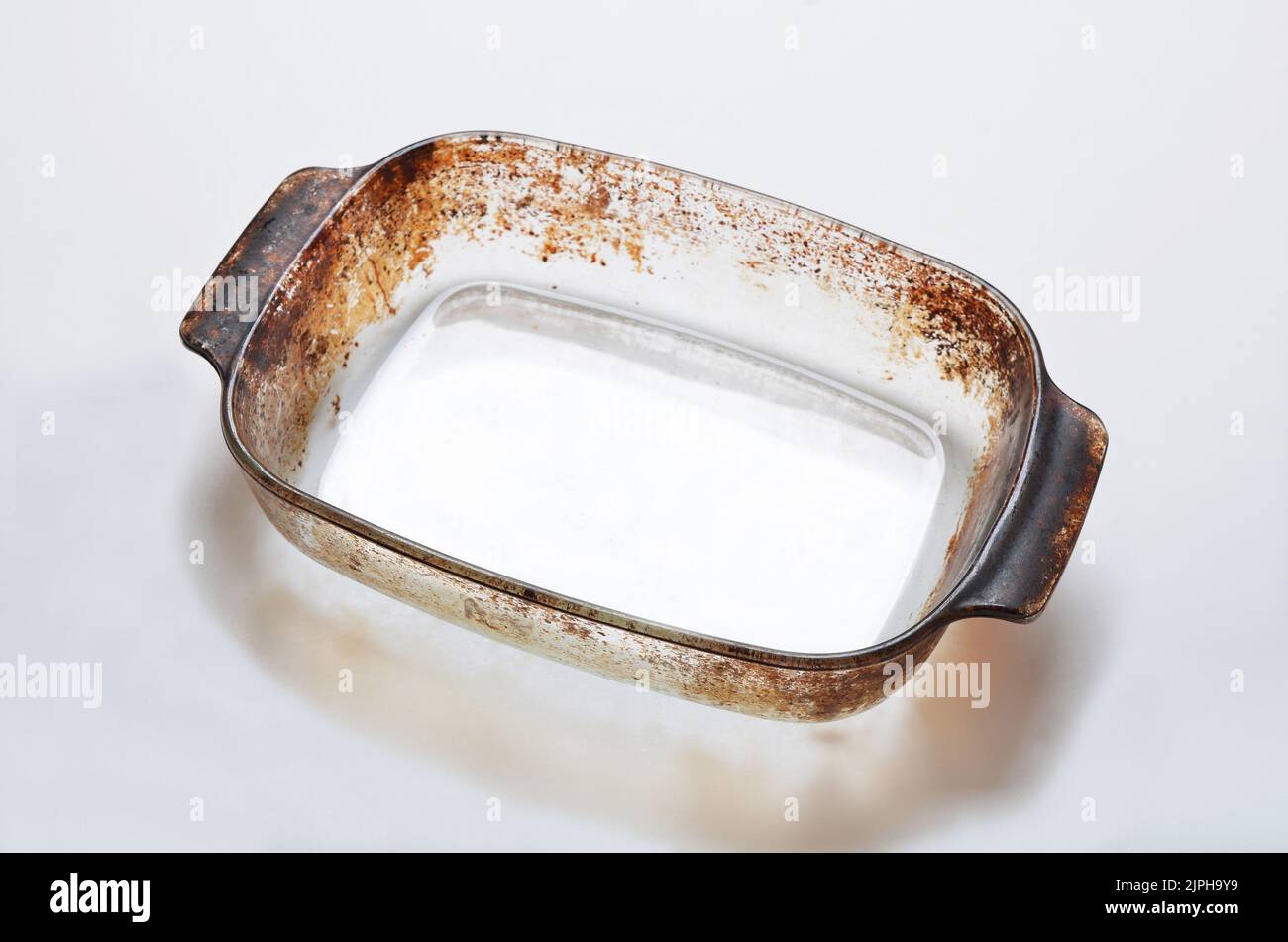 Glass pyrex oven dish used with burnt food on the edges on white ...