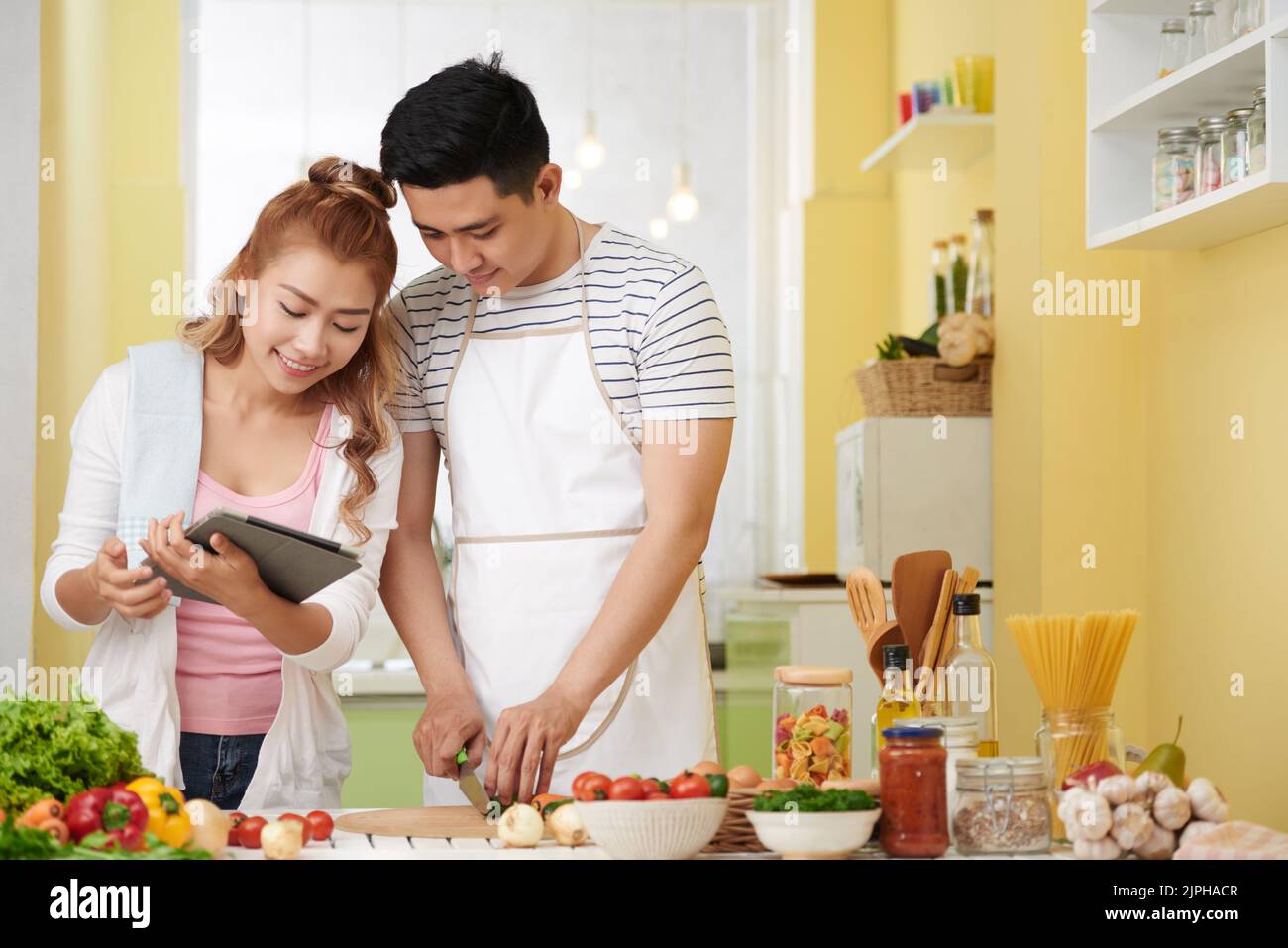 Vietnamese young couple following recipe on tablet computer Stock Photo ...