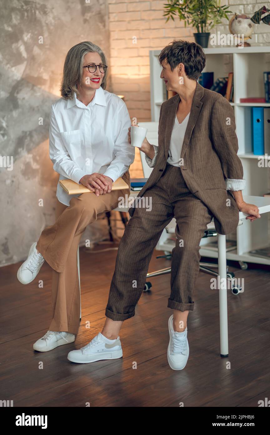 Two women talking in the offcie and looking involved Stock Photo - Alamy