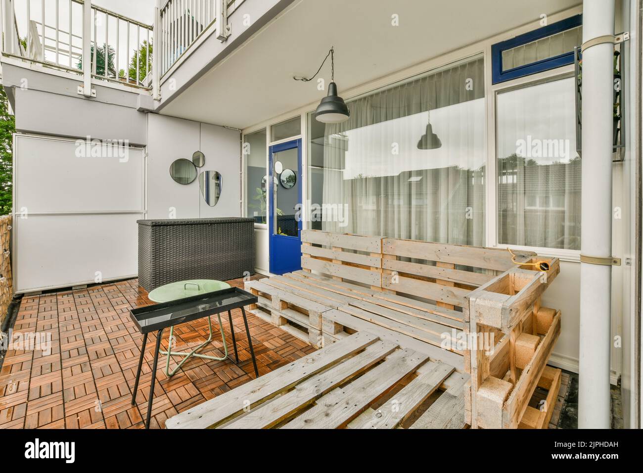 Narrow brick balcony with metal railings, wooden chair and door with ...