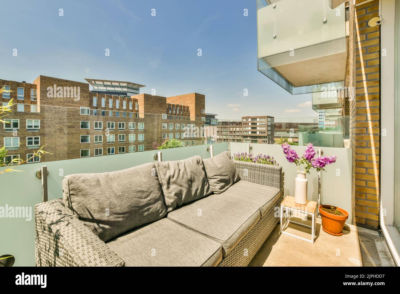 Narrow brick balcony with metal railings, wooden chair and door with ...