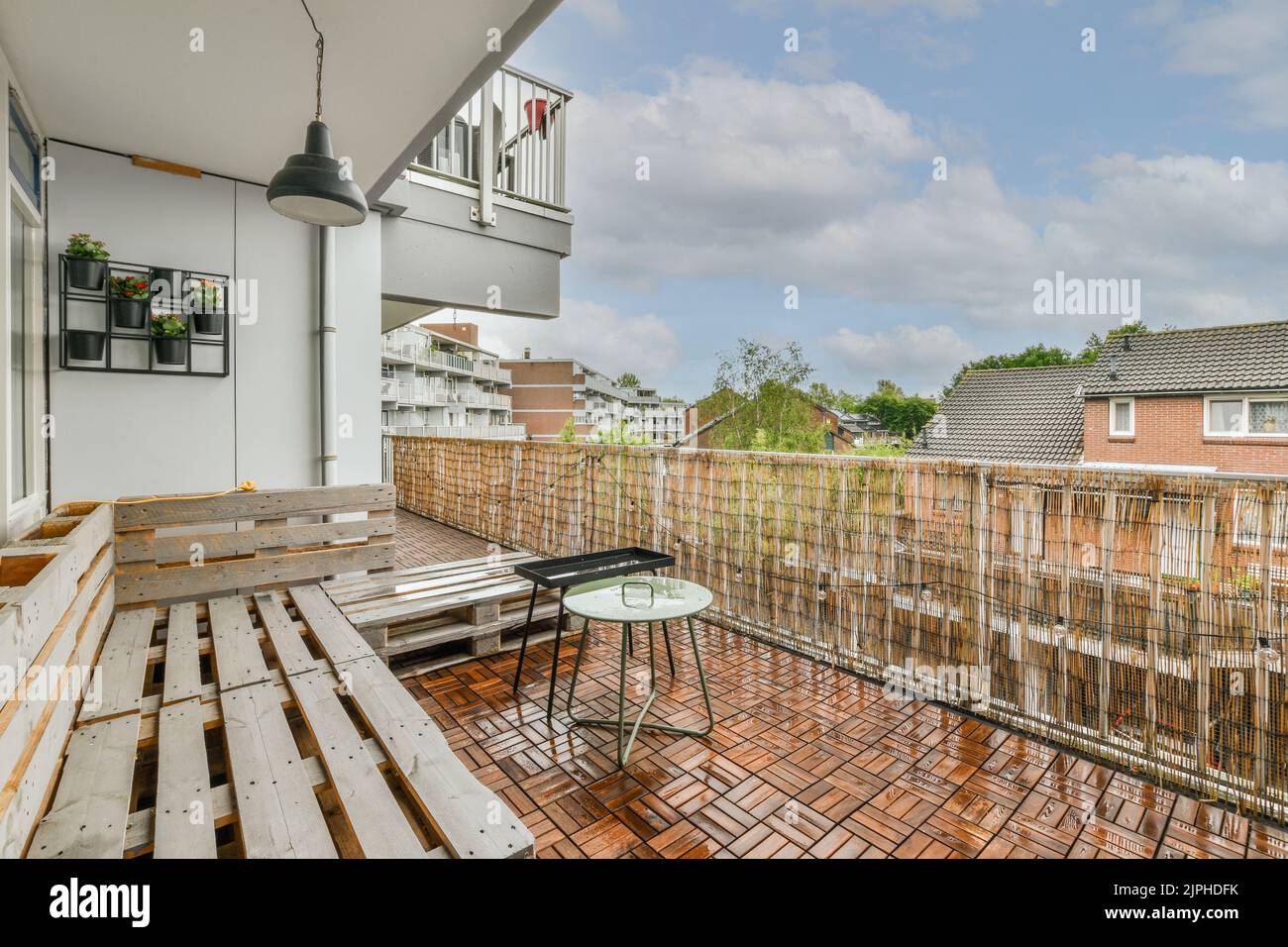 Narrow brick balcony with metal railings, wooden chair and door with ...