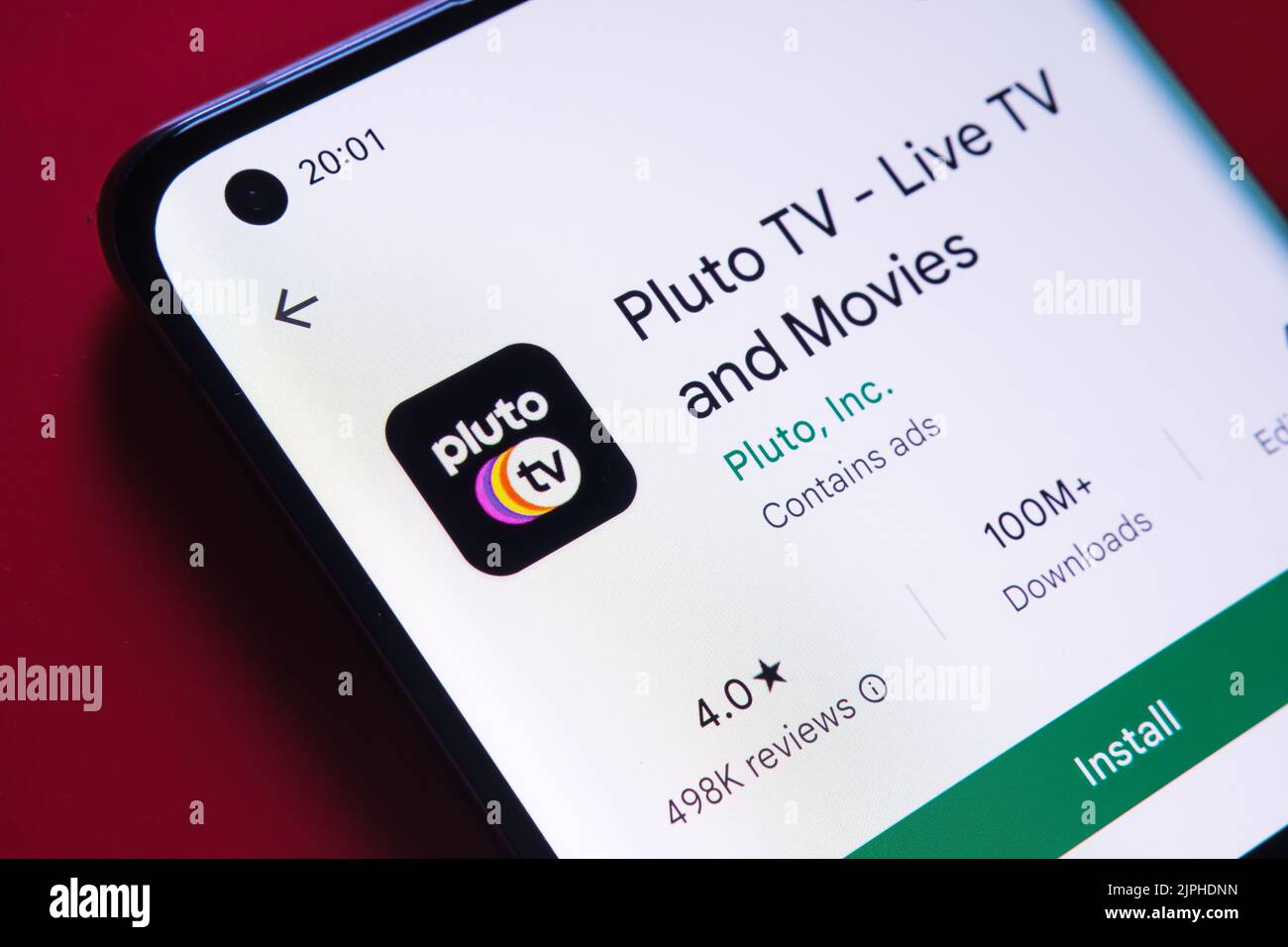 pluto TV app seen in Google Play Store on the smartphone screen placed on red background. Close ...