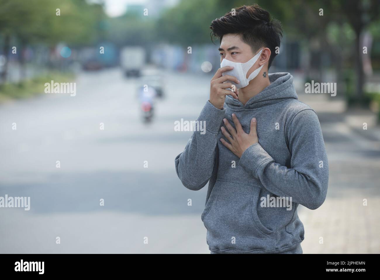 Young Vietnamese man having lungs problems beause of air pollution ...